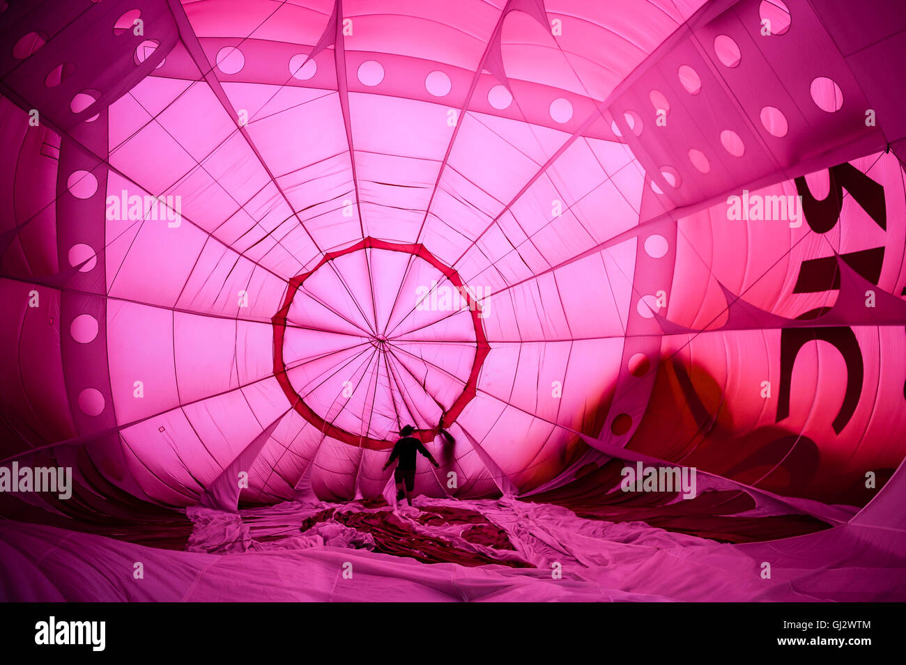A hot air balloon pilot checks rigging lines inside his square shaped ...
