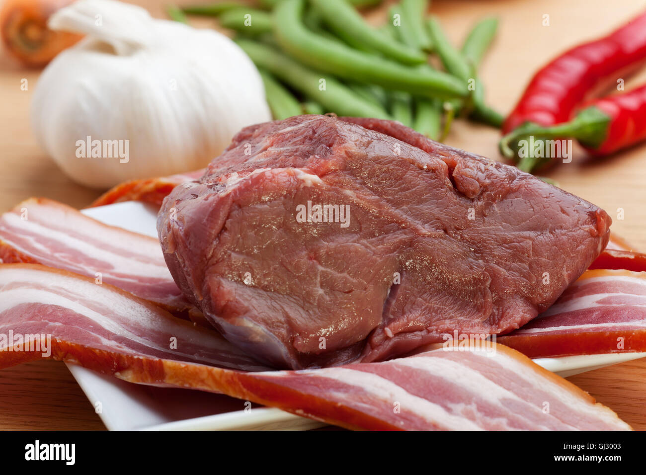 raw meat and bacon stripes on a wooden table Stock Photo - Alamy