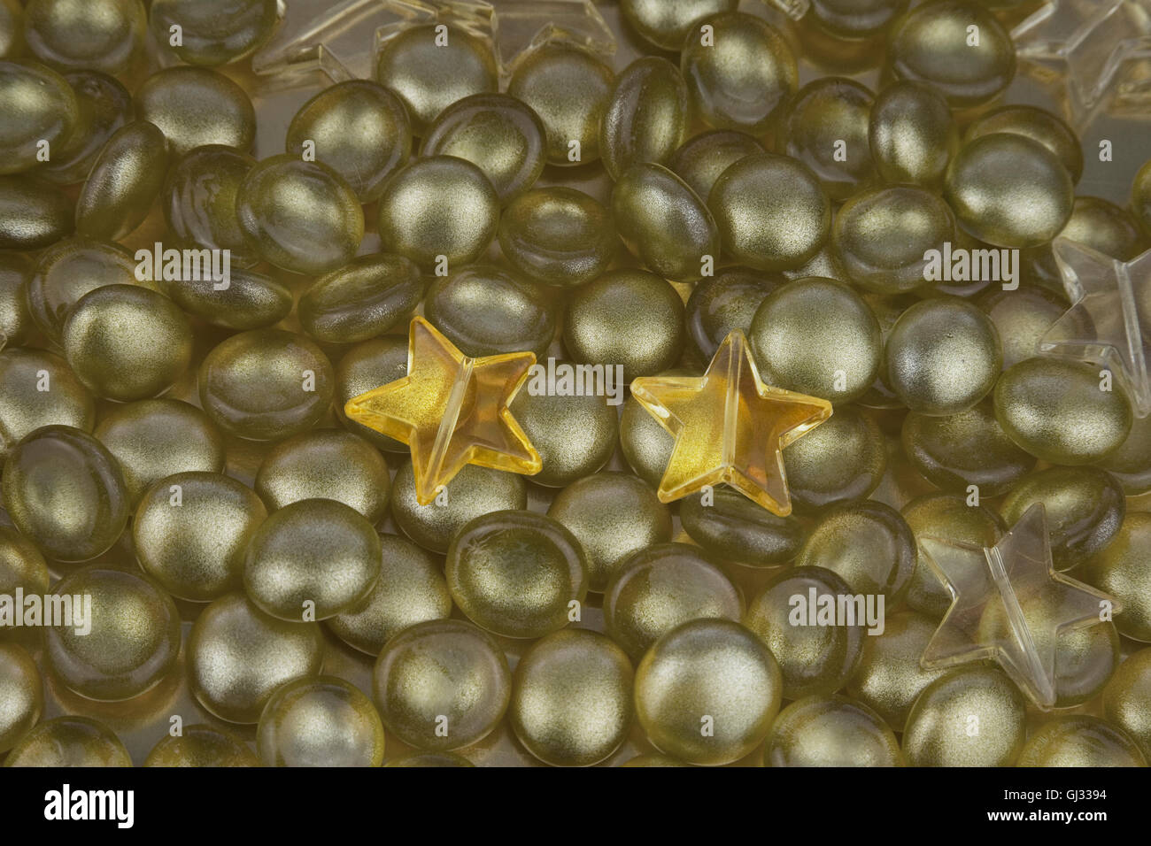Yellow clear glass stars on top of gold pebbles Stock Photo - Alamy
