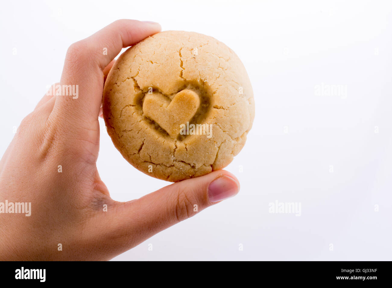 Hand holding a Light brown cookie with a pattern on a white background ...