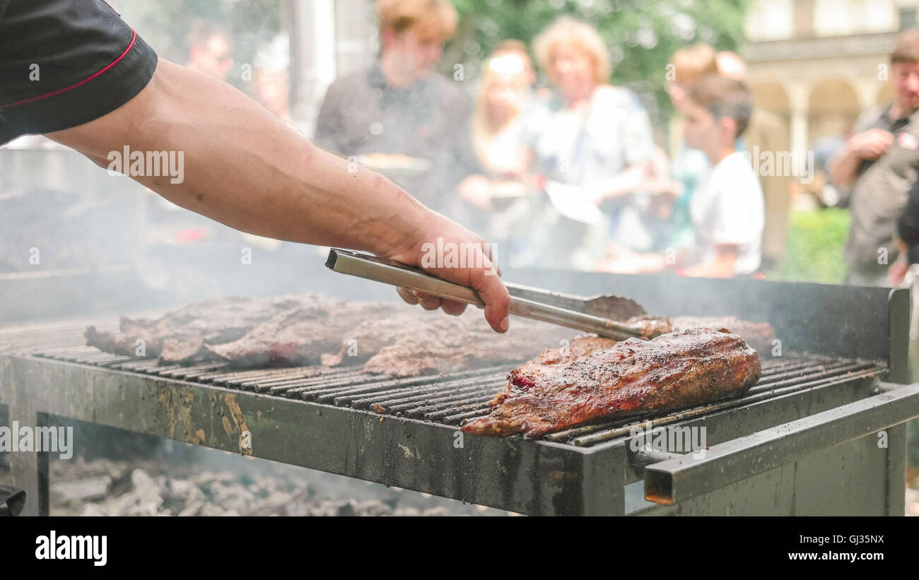 A man grabbing a piece of grilled meat Stock Photo - Alamy