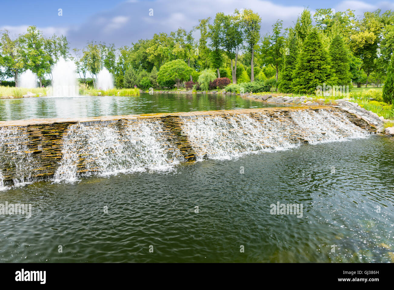 Beautiful waterfall in a park with human made pond, fountain and ...