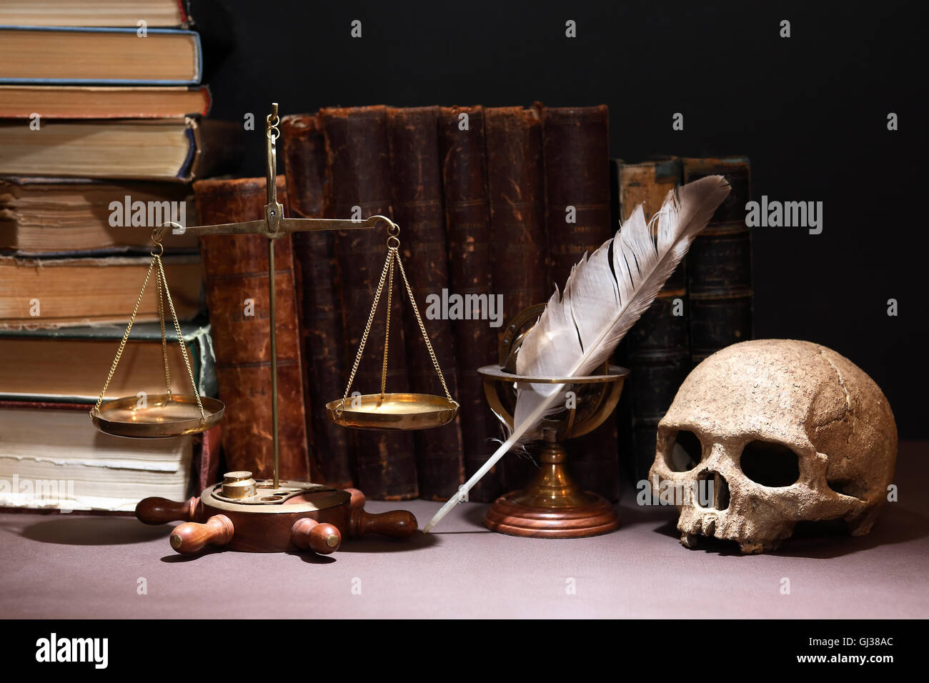 Old brass weight scales near skull and quill on books background Stock ...