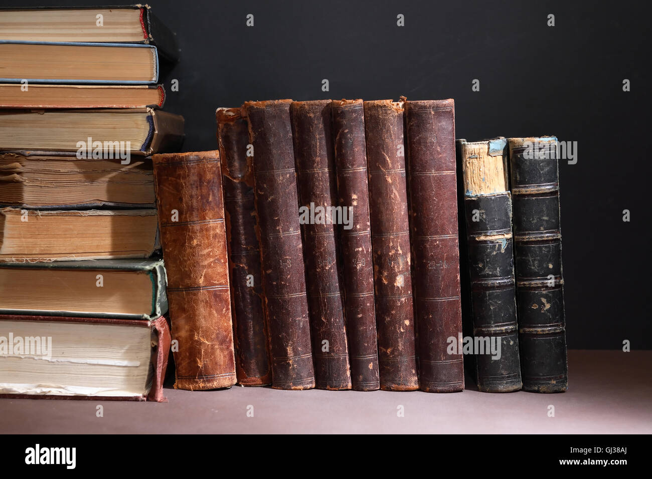 Vintage library. Old books in a row on dark background Stock Photo - Alamy