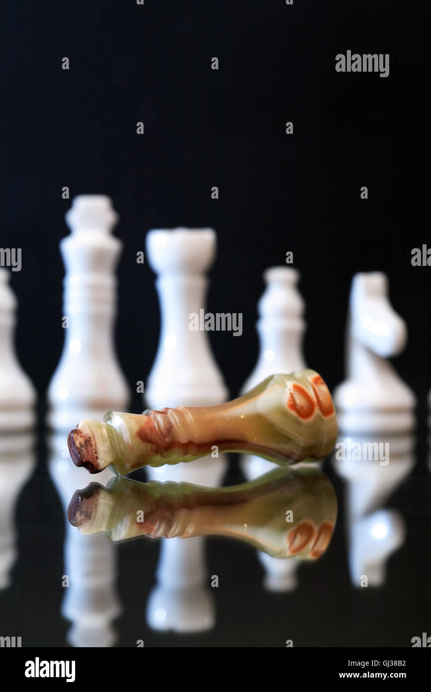 Chess Queen made from Onyx lying before lot of chessmen against dark ...