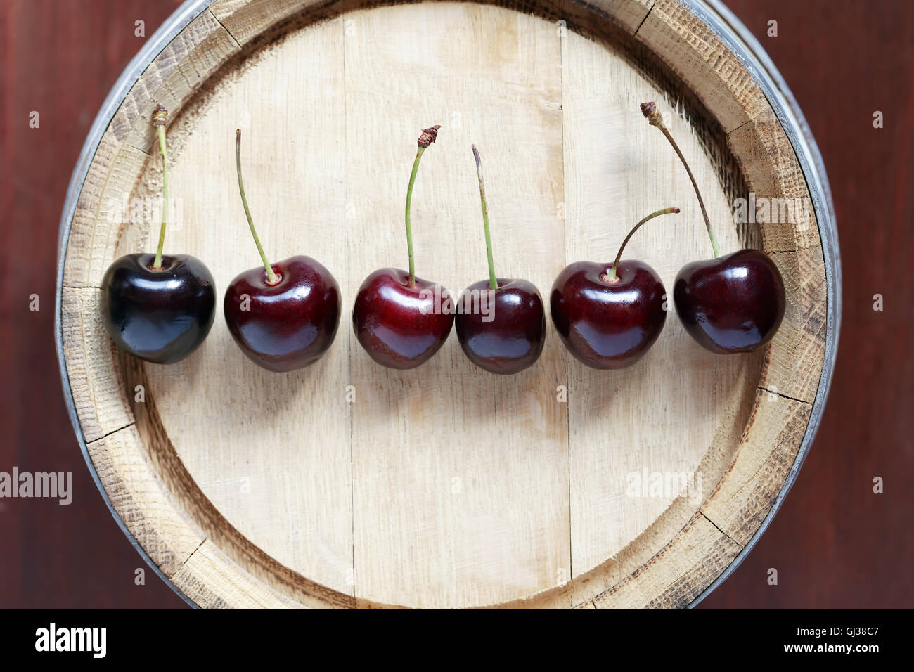 Farm concept. Few cherry fruits in a row on top of oak barrel Stock ...