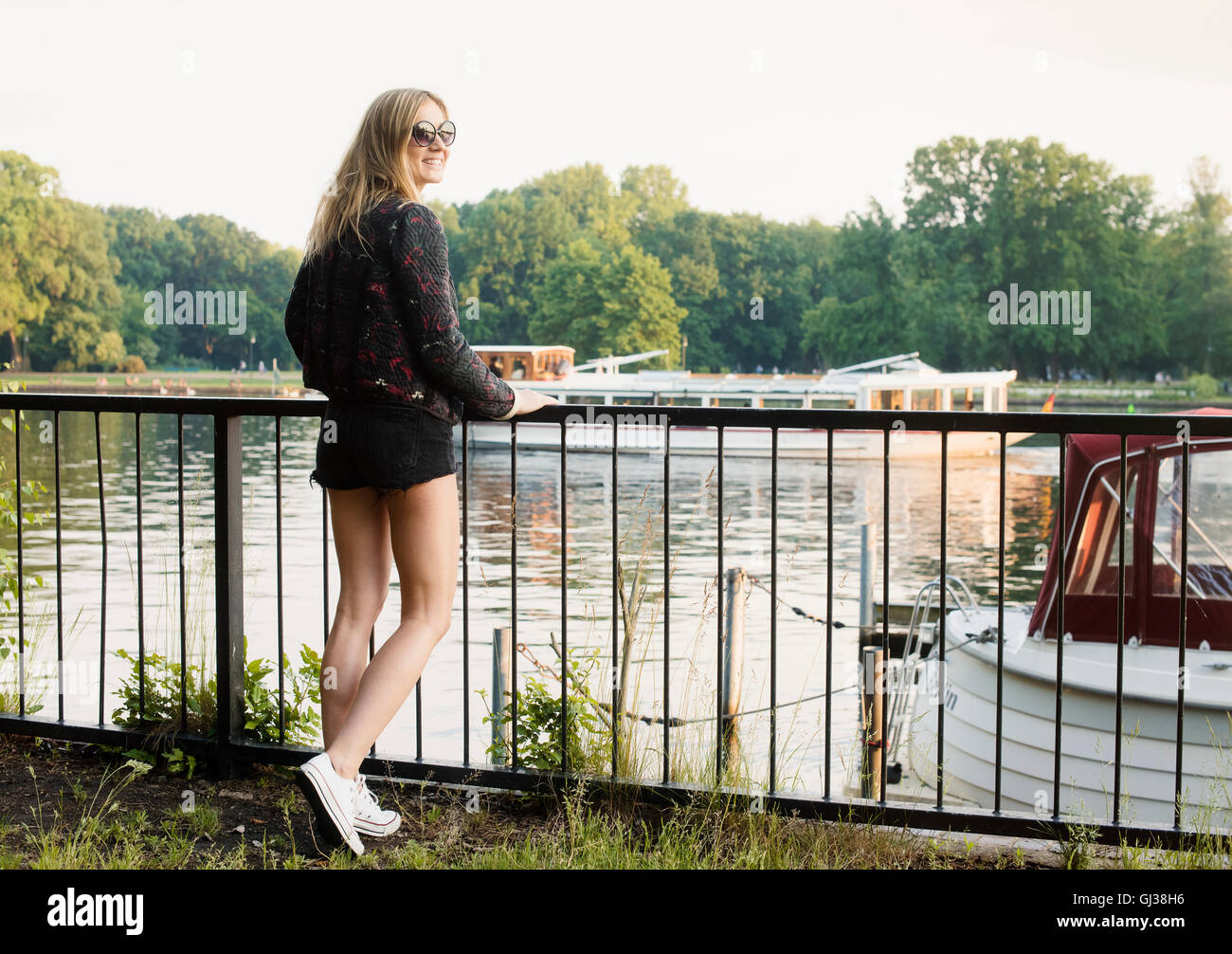 Young leaning on railings at waterfront, looking over shoulder Stock ...