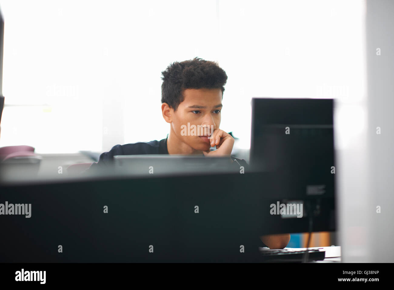 Young male college student at desk reading computer Stock Photo - Alamy