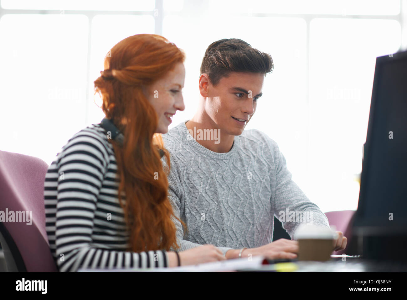 Young male and female college students at computer desk looking at ...
