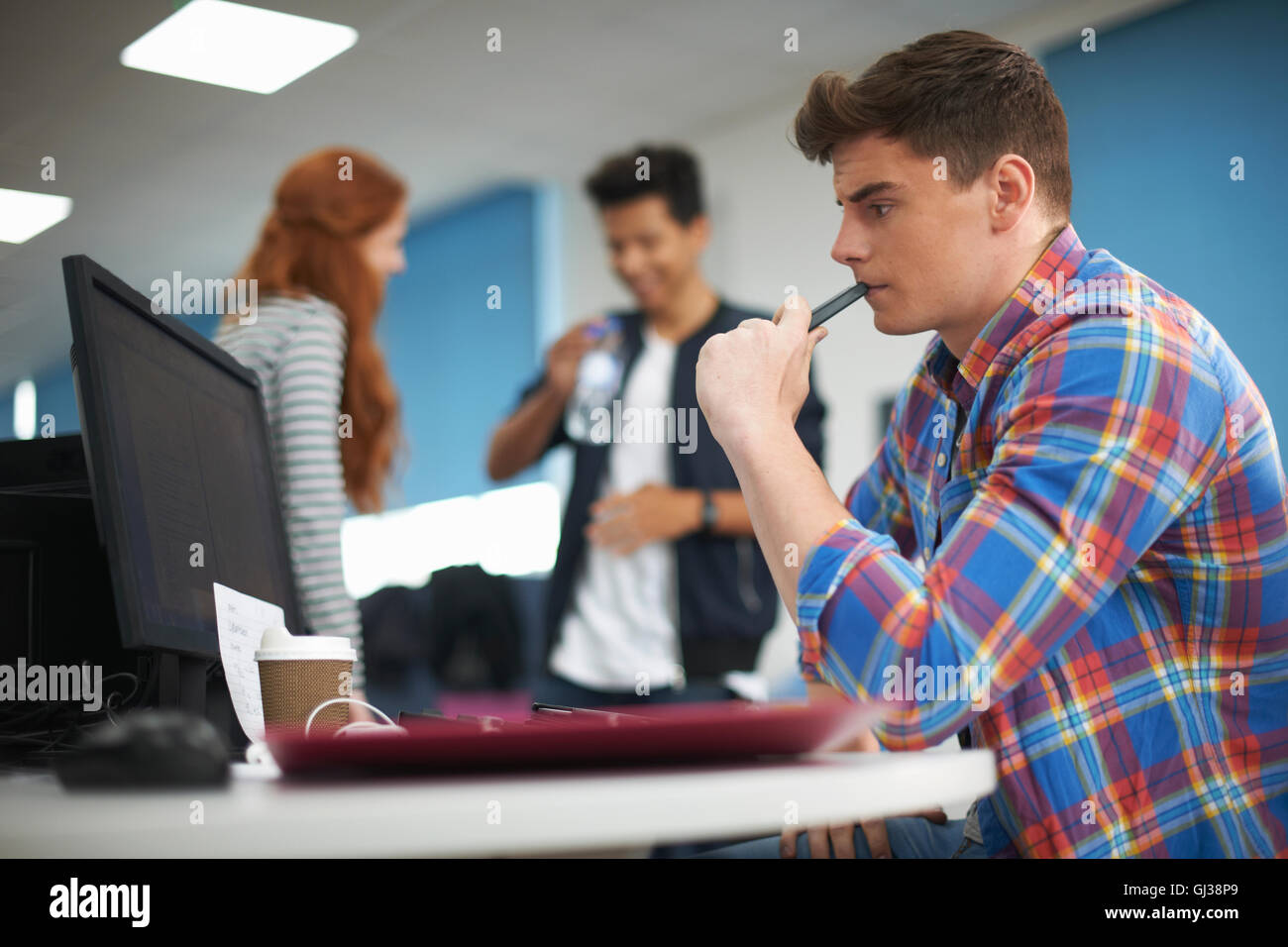 Young male college student at computer desk looking at computer Stock ...