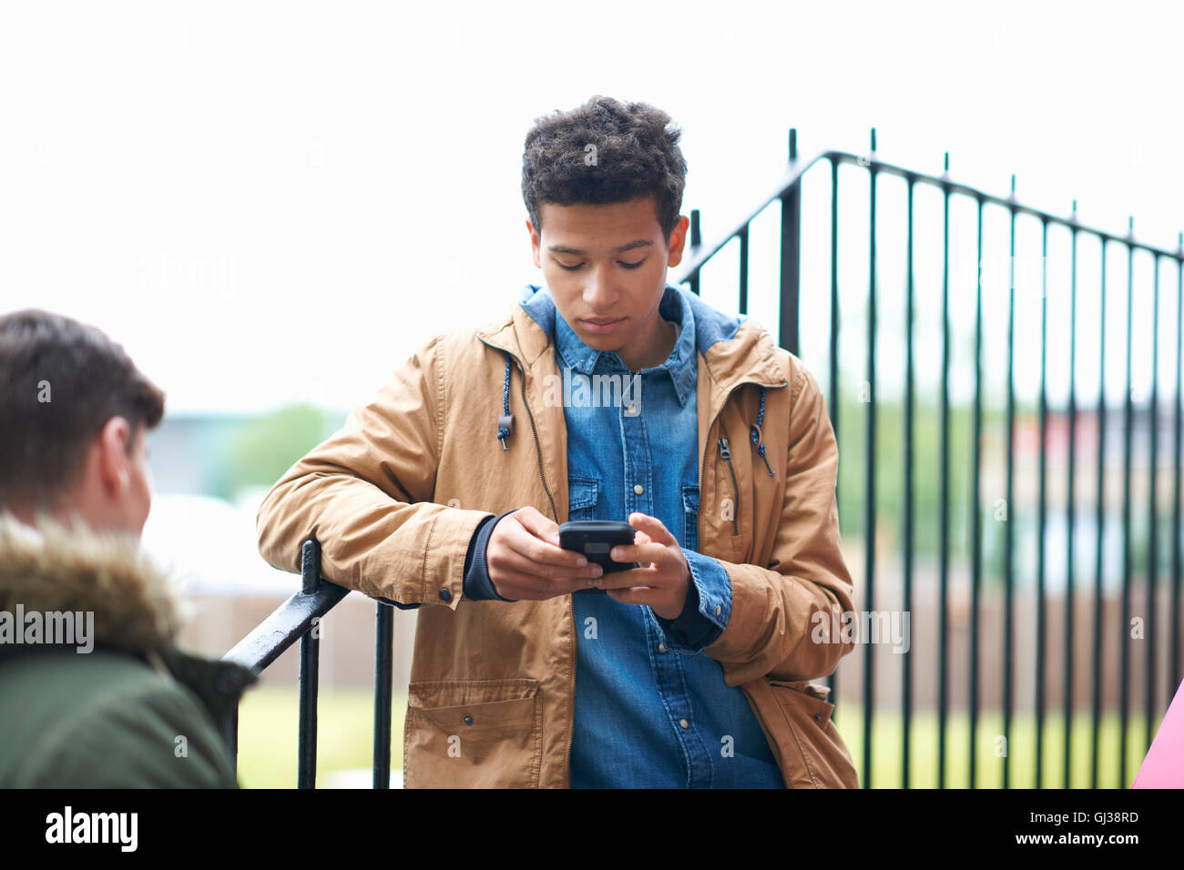 Young male college student reading smartphone text on campus Stock ...