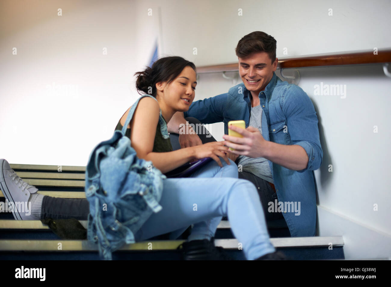 Young college student couple reading smartphone texts on stairway Stock ...