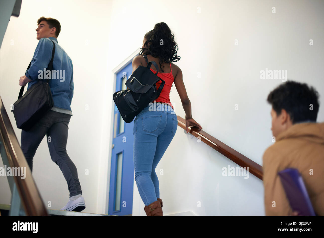 Three young adult college students moving up stairway Stock Photo - Alamy