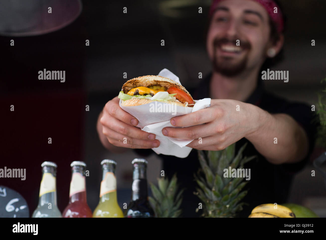 Young man serving hamburger from fast food van Stock Photo - Alamy