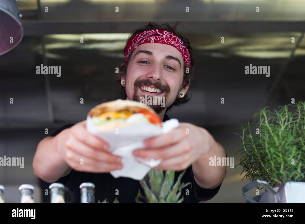 Young man serving hamburger from fast food van Stock Photo - Alamy
