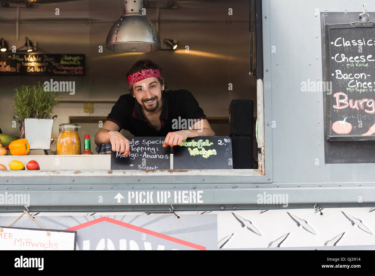 Portrait of young man at hatch of fast food van Stock Photo - Alamy
