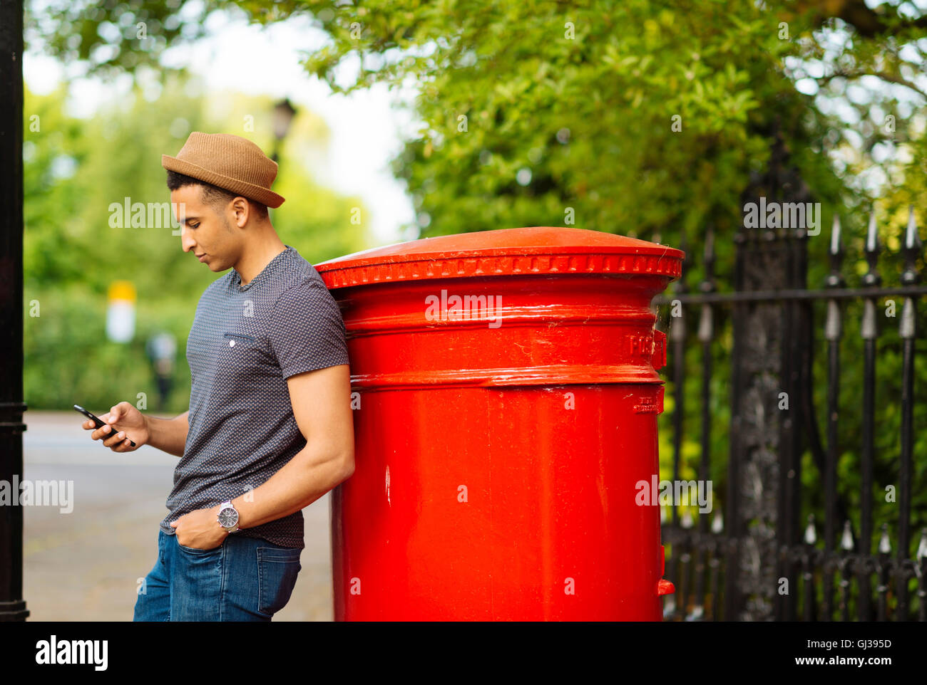 Man leaning against mailbox using smartphone Stock Photo - Alamy
