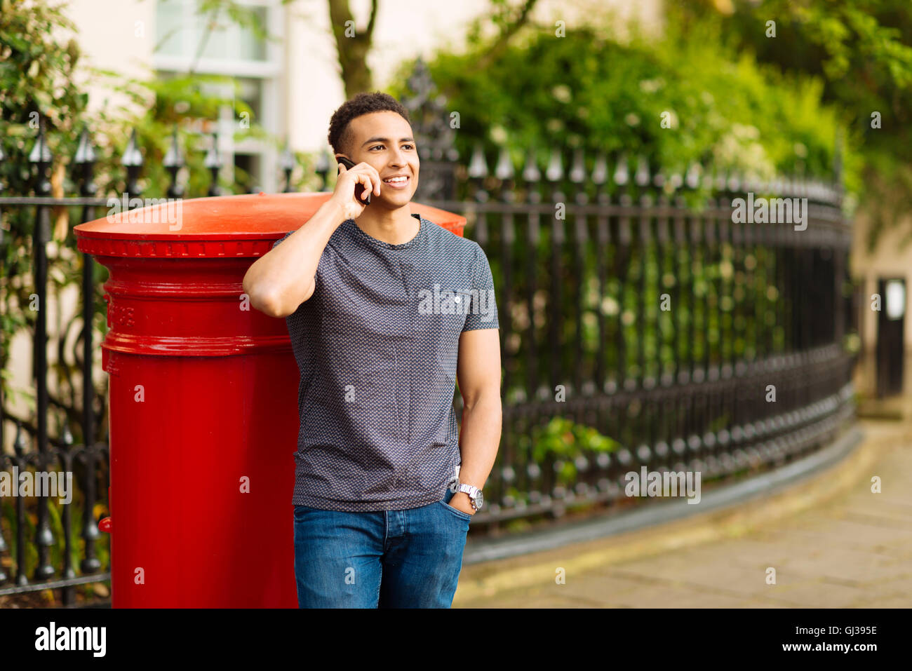 Man leaning against mailbox using smartphone Stock Photo - Alamy