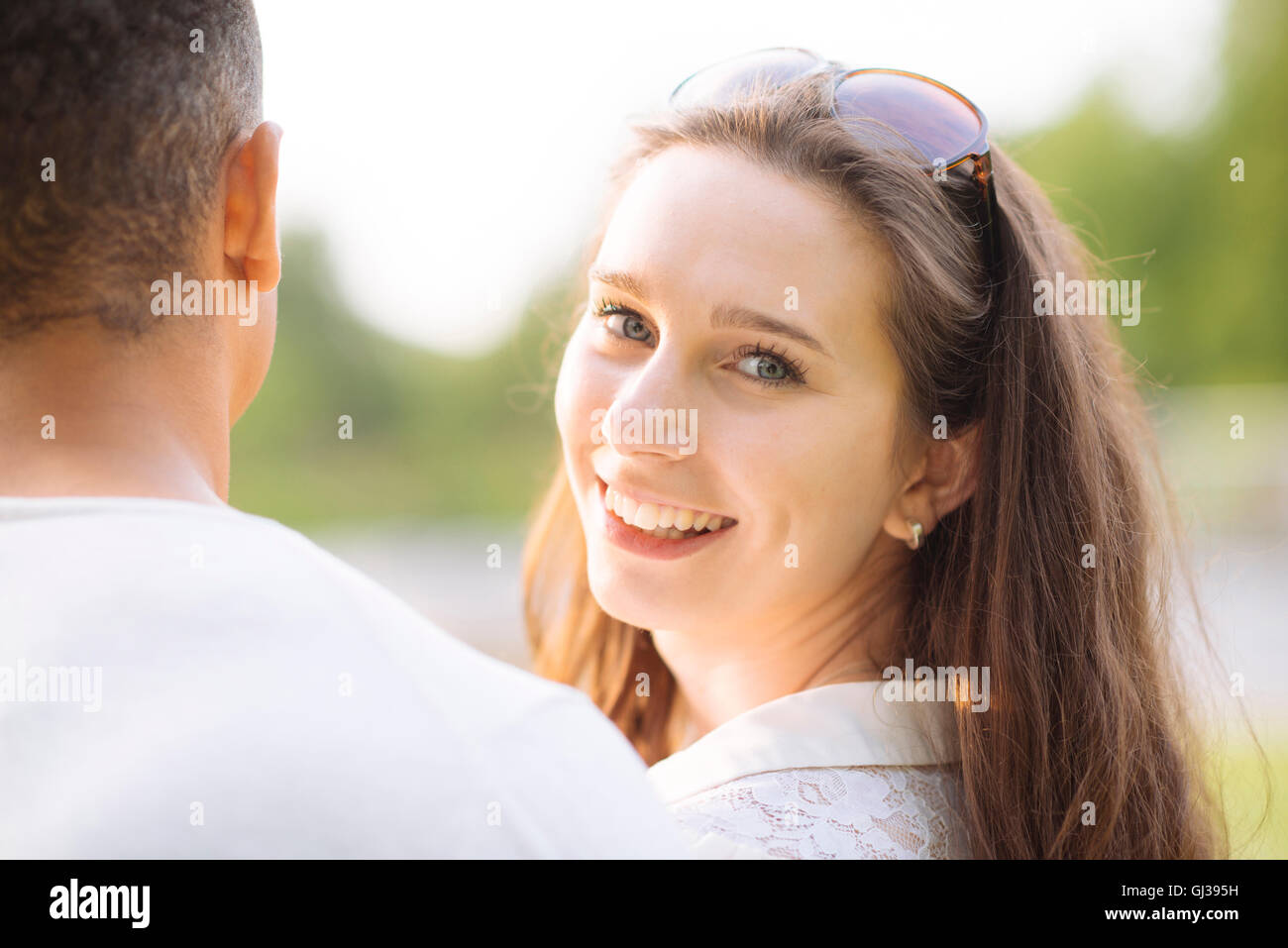 Young woman looking over shoulder at camera smiling Stock Photo - Alamy