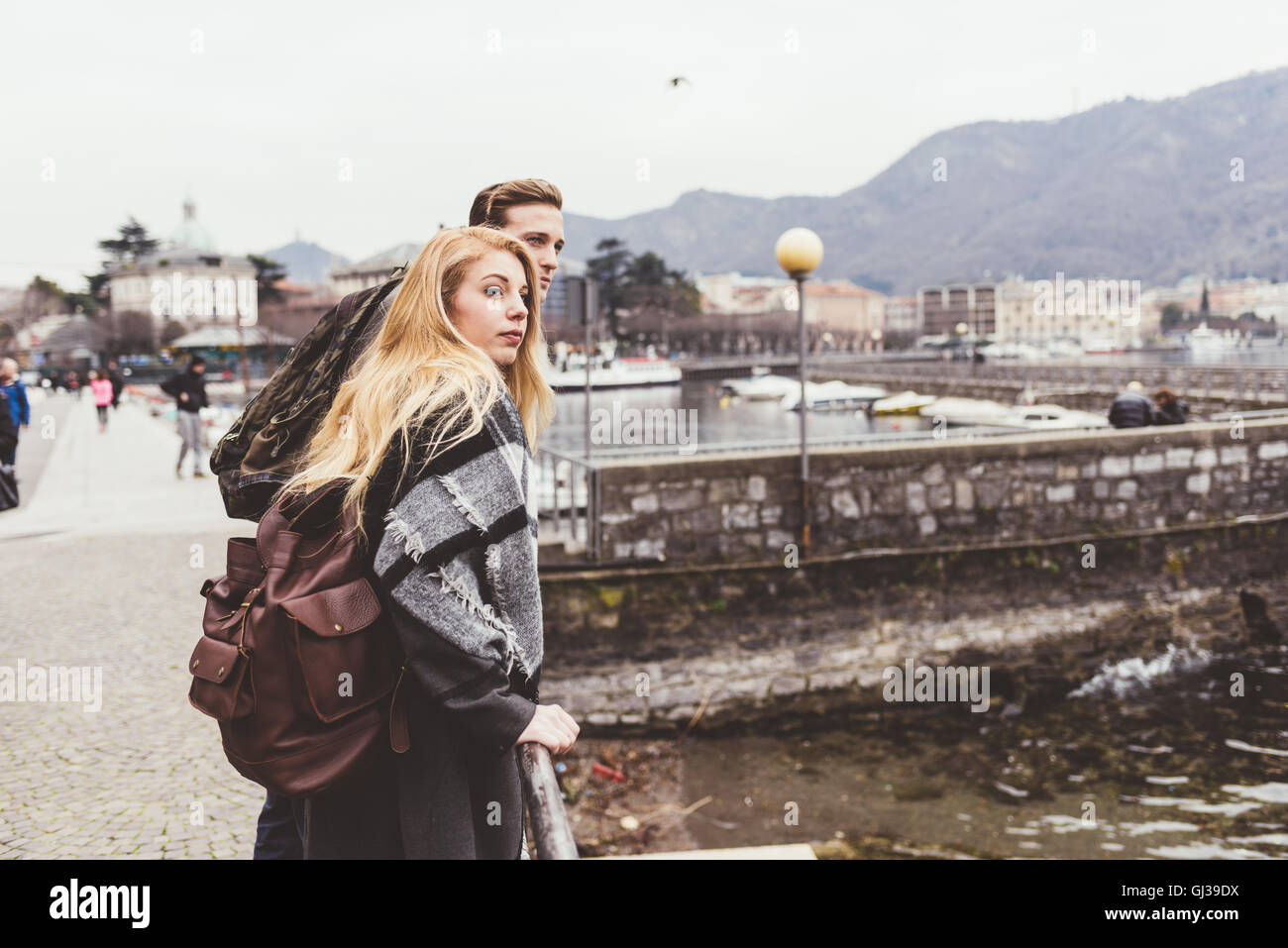 Young couple looking over their shoulders at lakeside, Lake Como, Italy ...