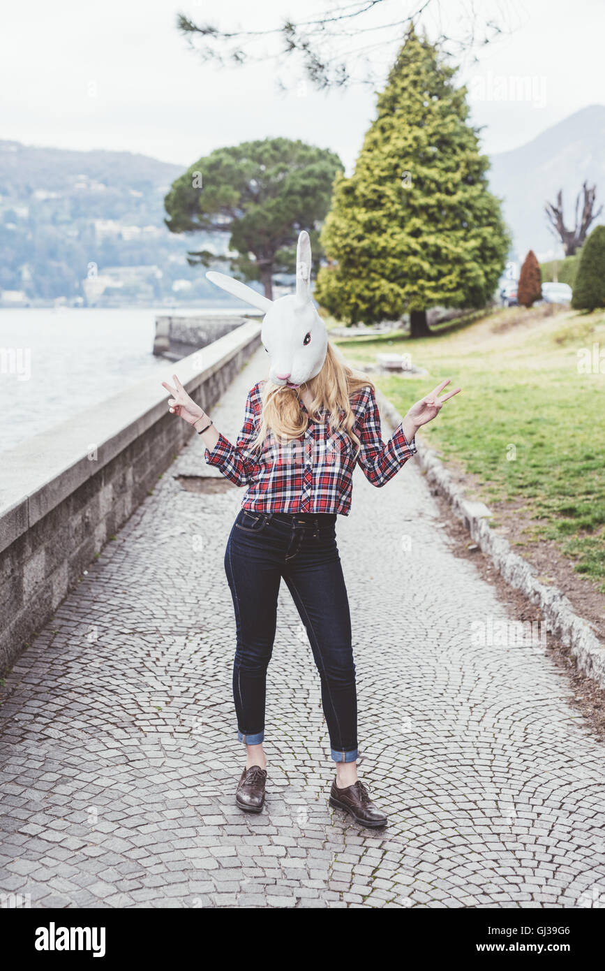 Portrait of woman wearing rabbit mask making peace sign, Lake Como ...