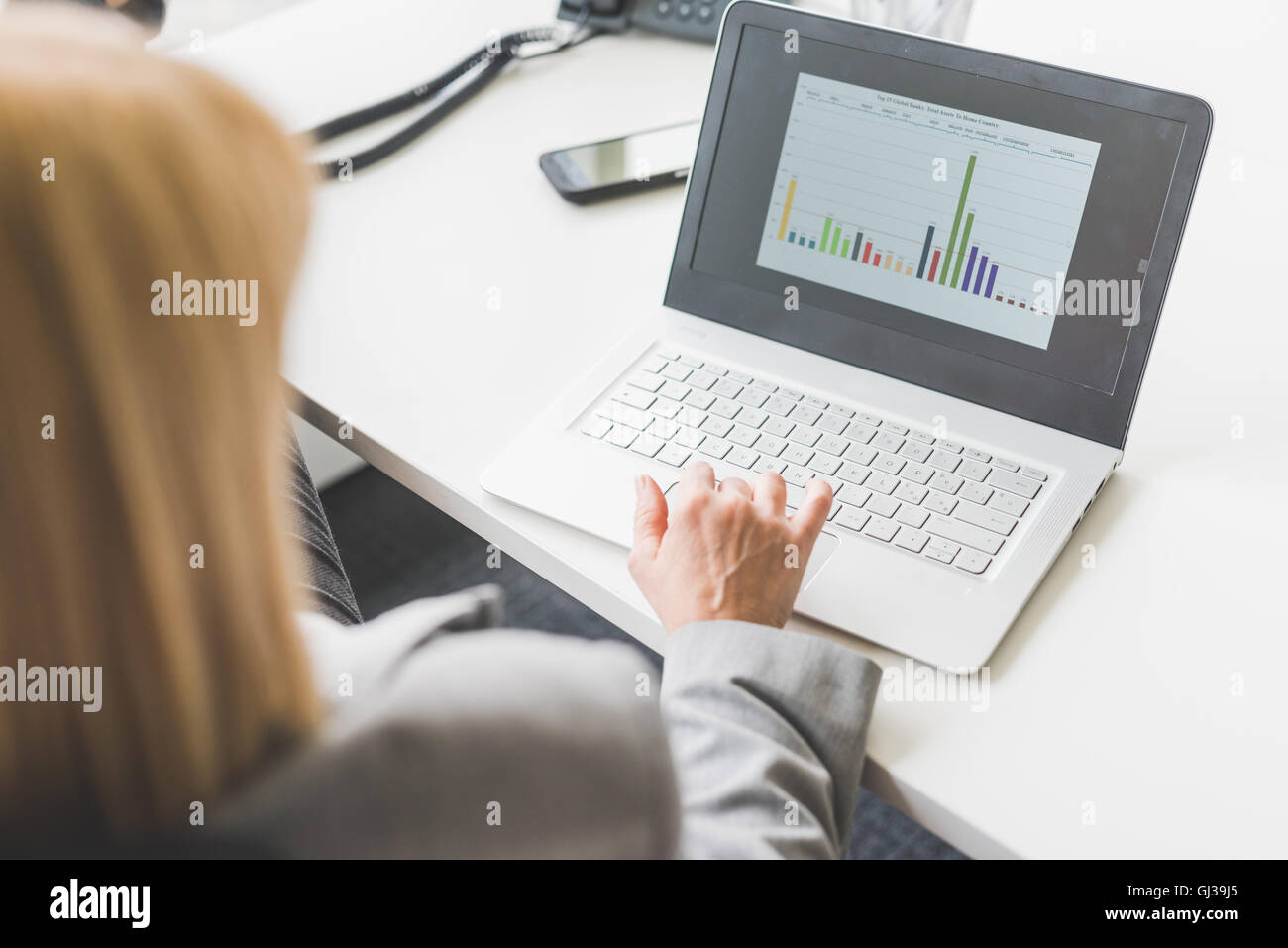 Over shoulder view of businesswoman typing on laptop at office desk ...