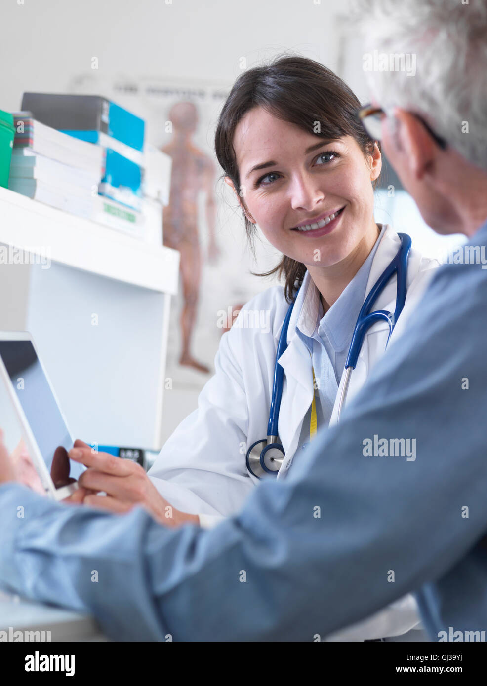 Doctor sharing health information on digital tablet with patient in ...
