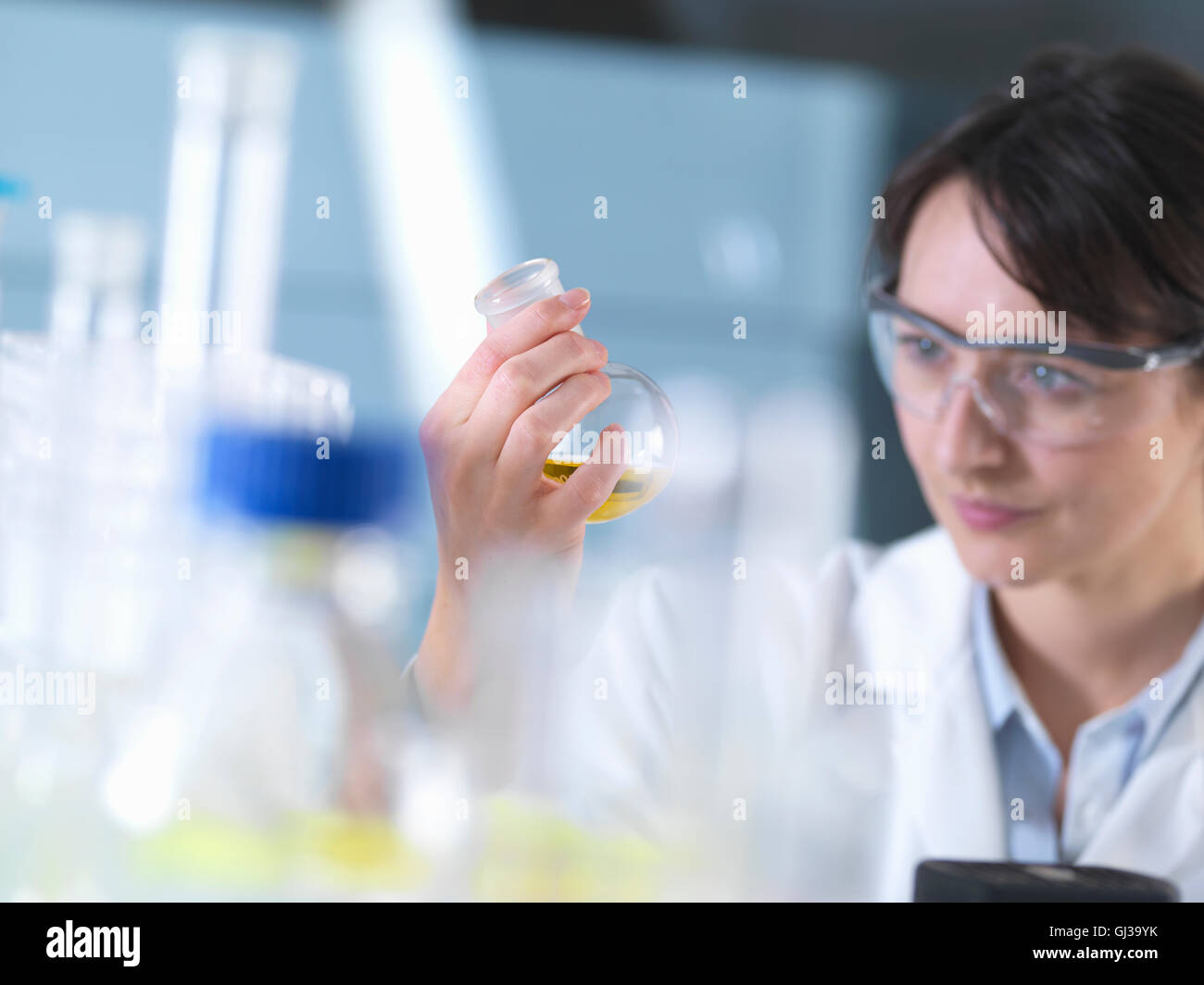 Scientist viewing chemical formula in beaker during experiment in ...