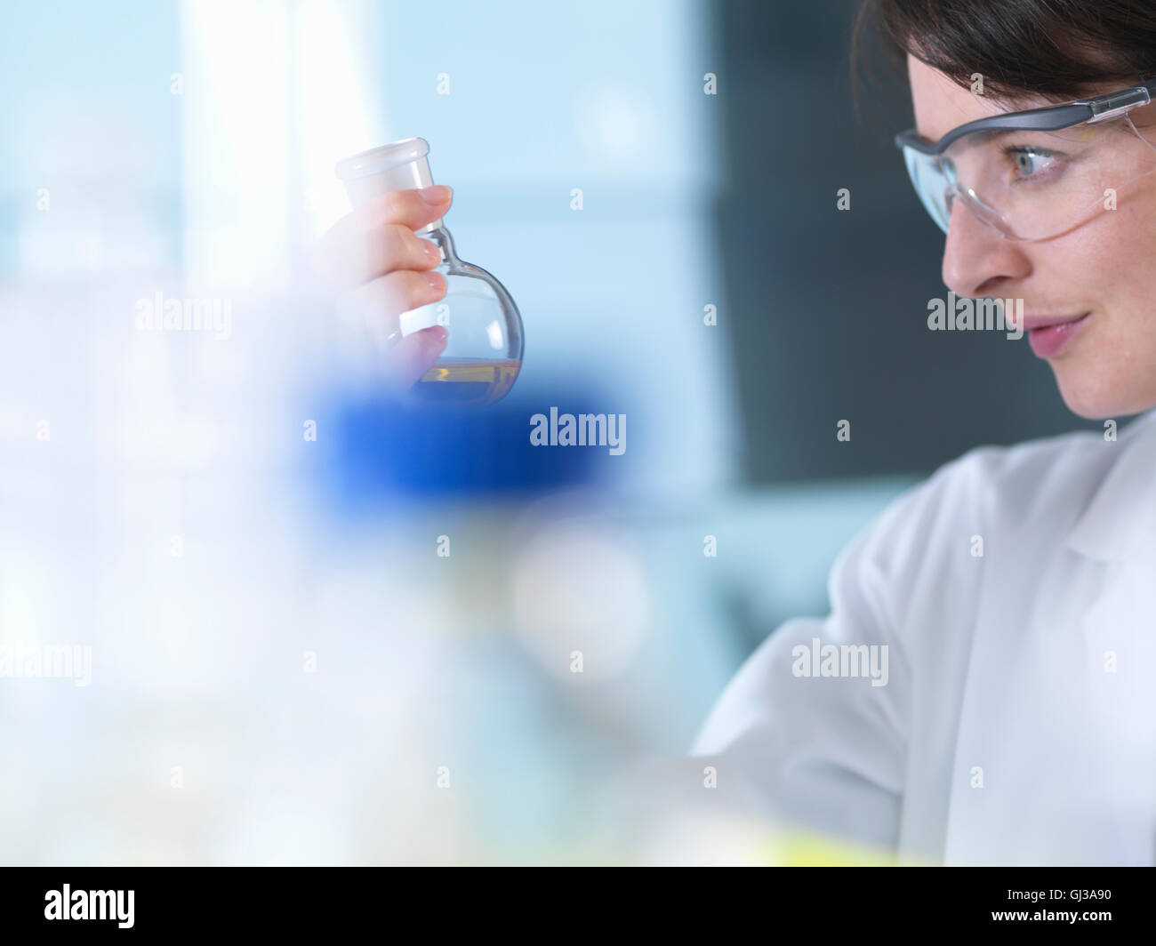Scientist viewing chemical formula in beaker during experiment in ...