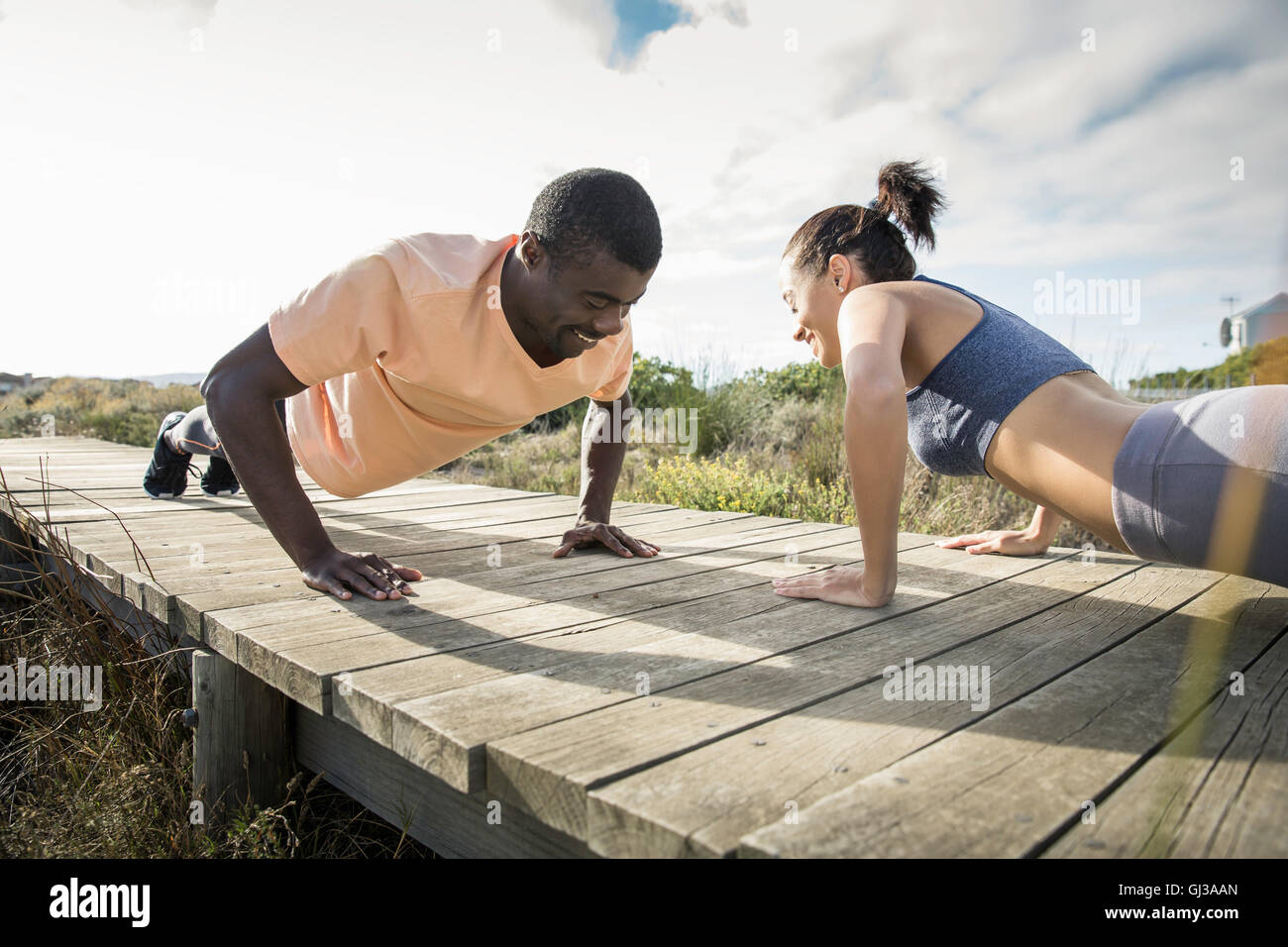Couple doing push ups on wooden pathway Stock Photo - Alamy