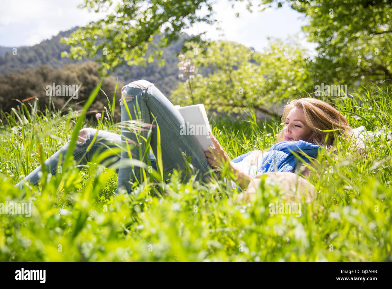 Woman lying on grass reading Stock Photo - Alamy