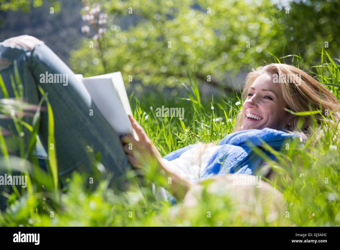 Woman lying on grass reading Stock Photo - Alamy