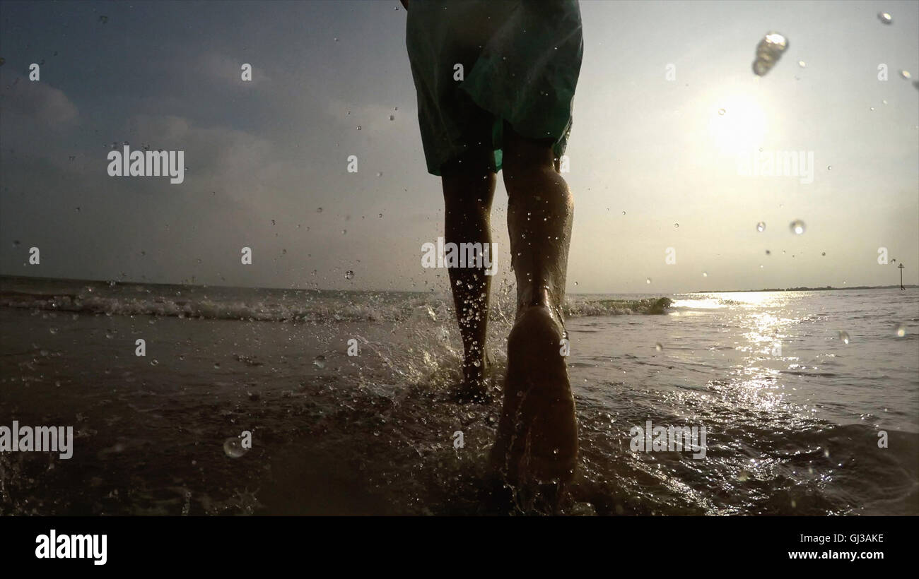 Legs of woman on coastline walking in ocean Stock Photo - Alamy