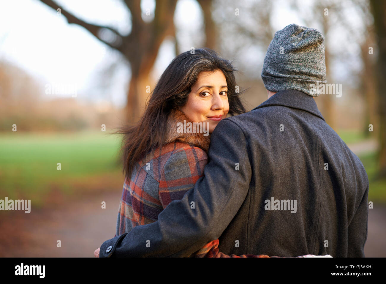 Mature couple with arms around each other looking over shoulder at ...