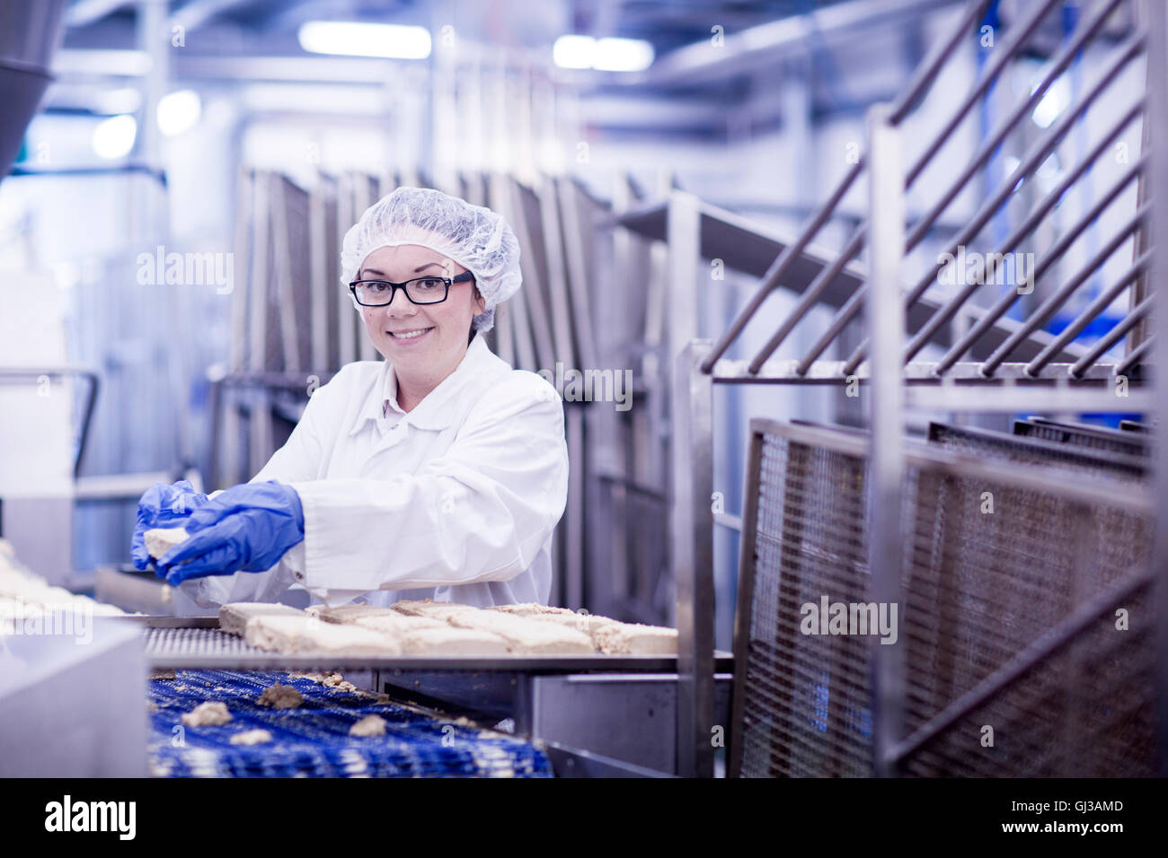 Woman working in food production factory looking at camera smiling ...