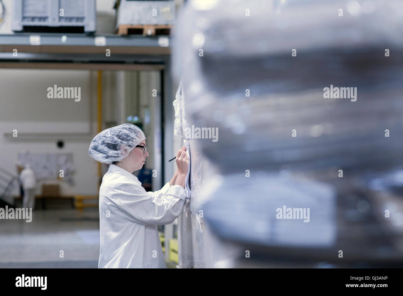 Factory worker writing on paperwork Stock Photo - Alamy