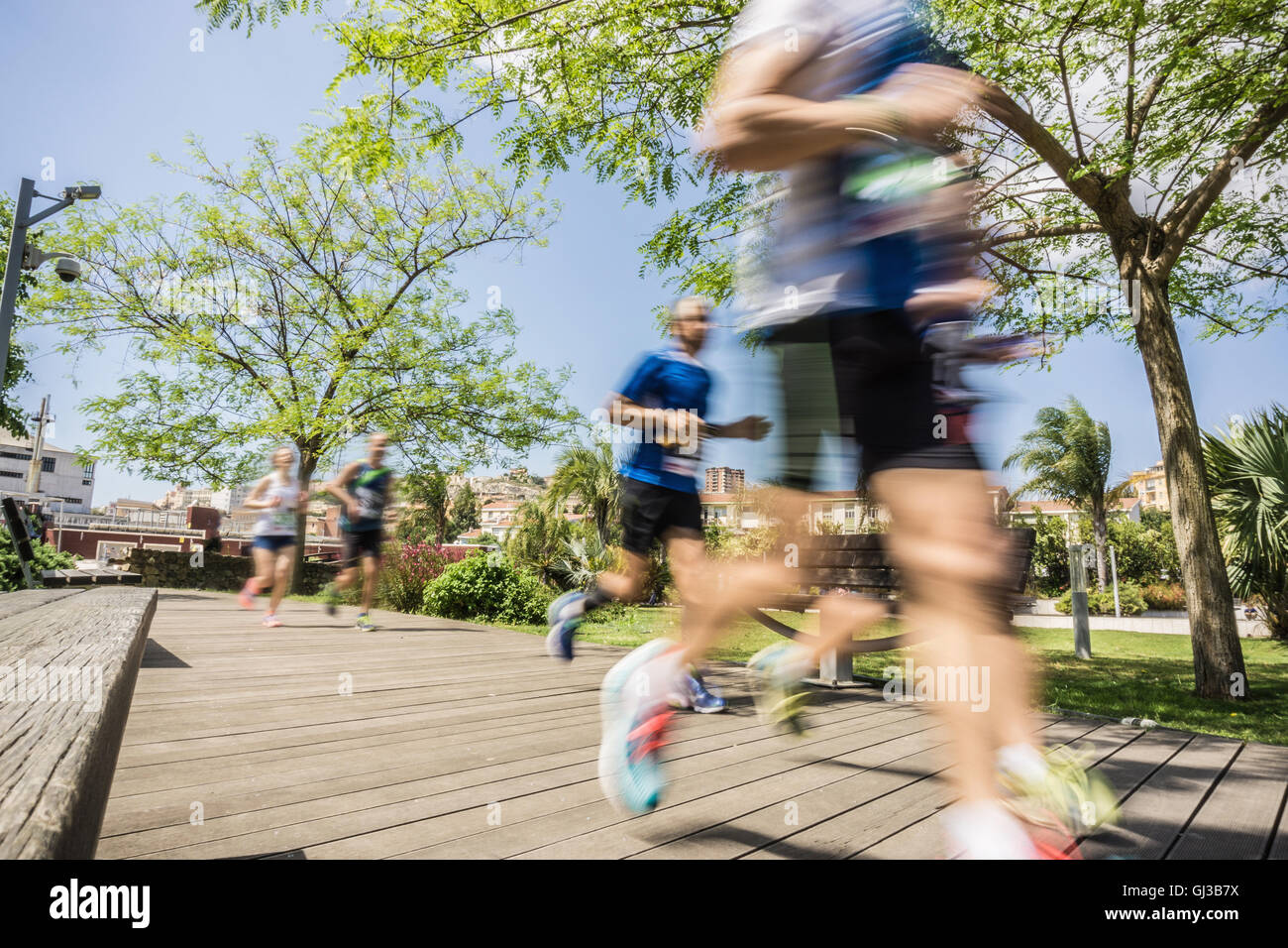 Blurred motion of runners running on park boardwalk Stock Photo - Alamy