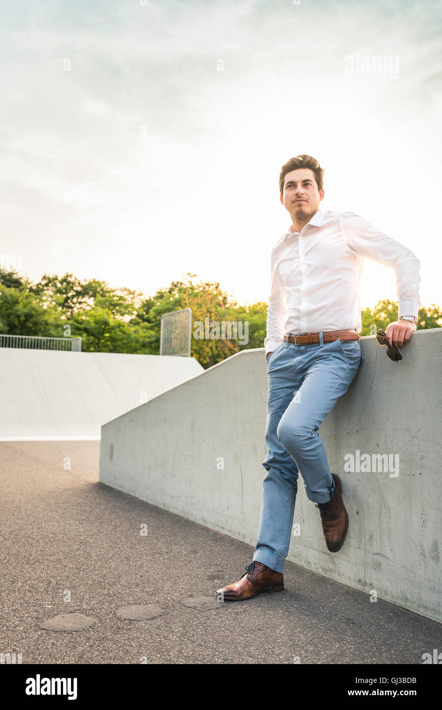 Smart young man leaning against wall Stock Photo - Alamy