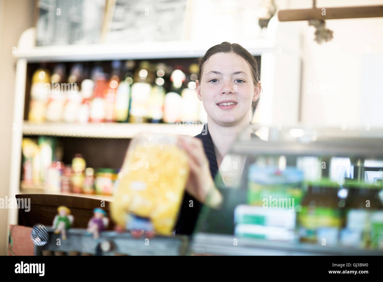 Portrait of young female shop assistant at corner shop counter Stock ...