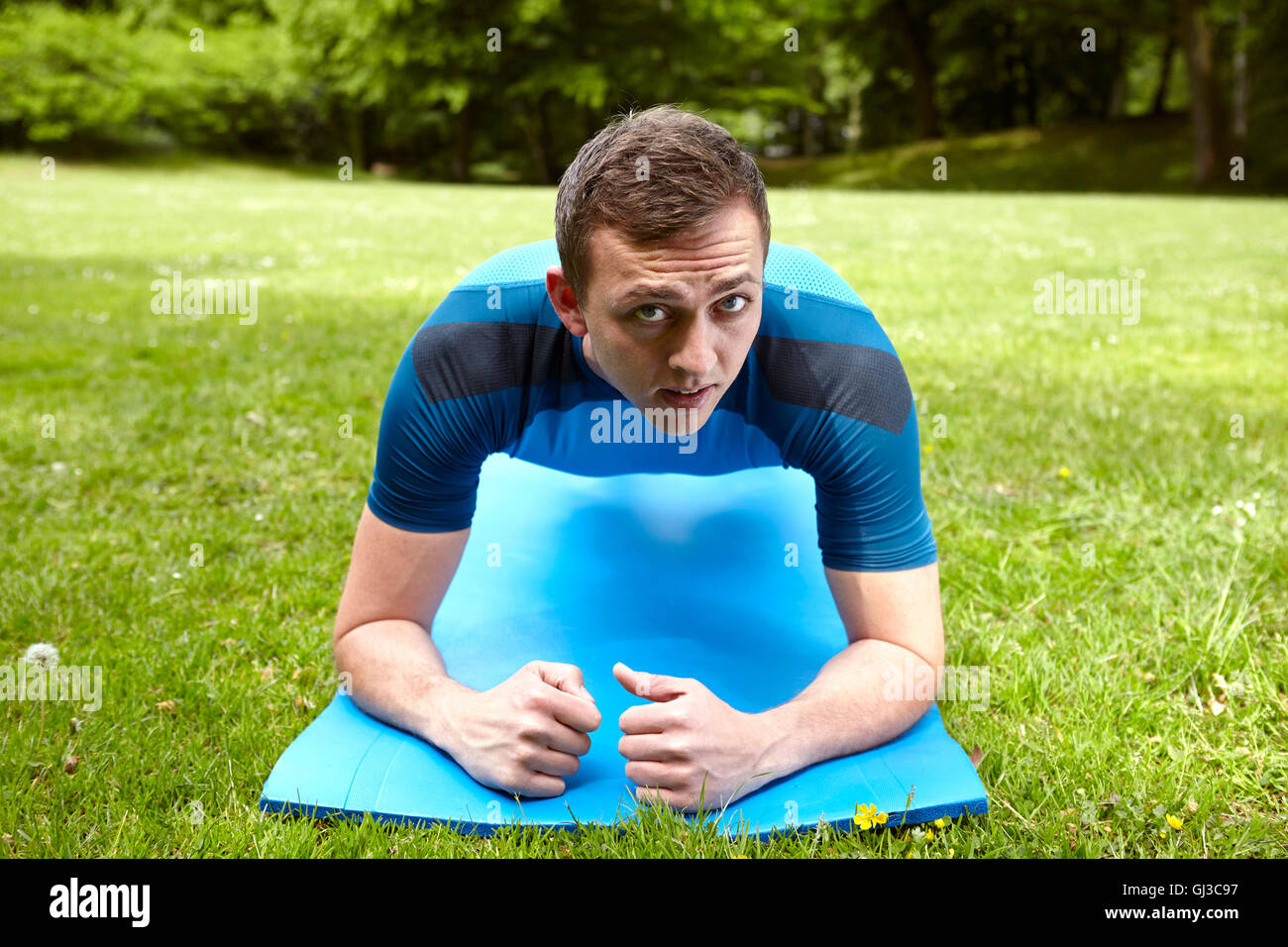 Young man training in park, doing push ups on exercise mat Stock Photo ...