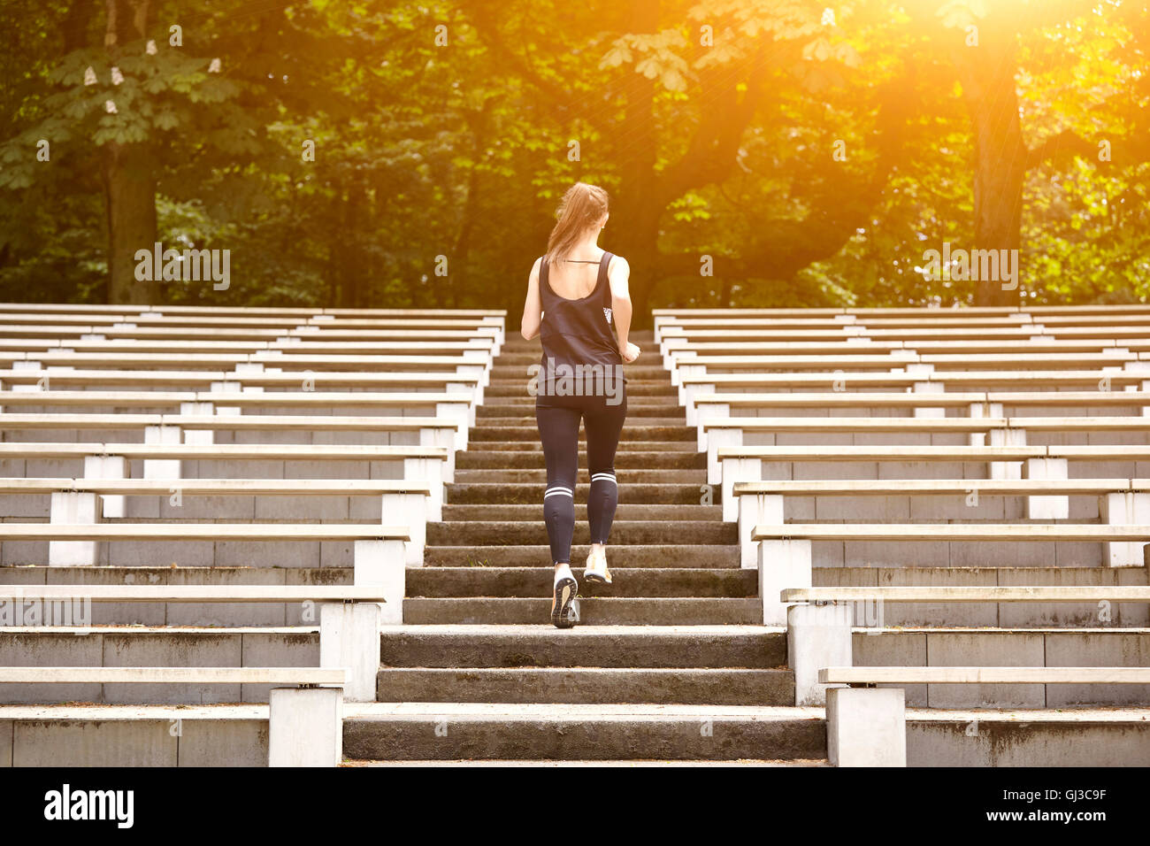 Rear view of young woman training, running up stadium stairway Stock ...