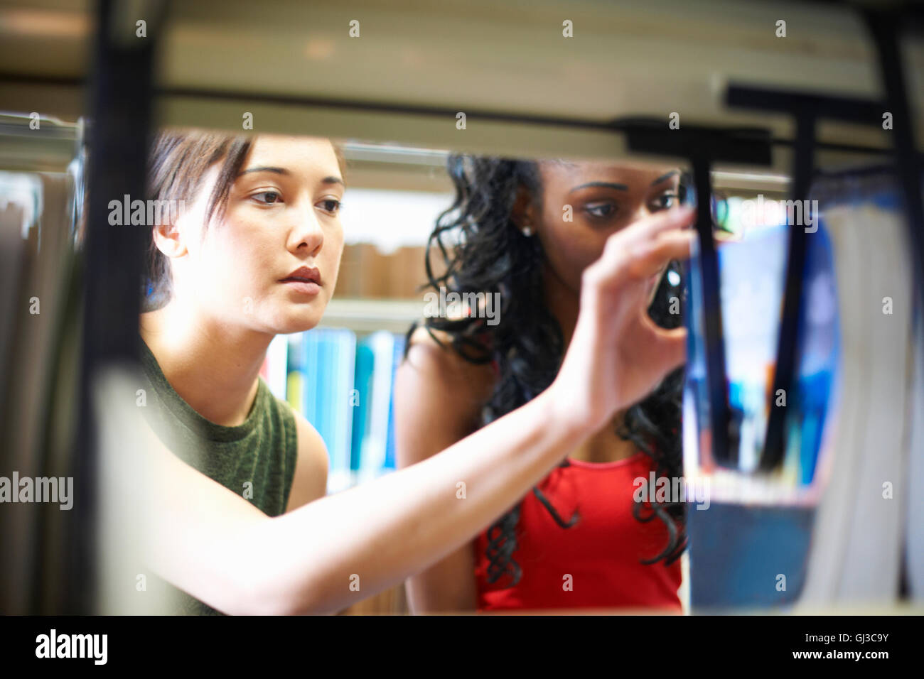 Two young female college students searching library shelves Stock Photo ...