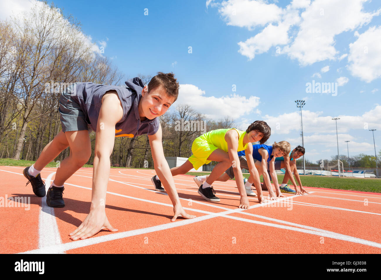 Four teenage runners lined up ready to race Stock Photo - Alamy