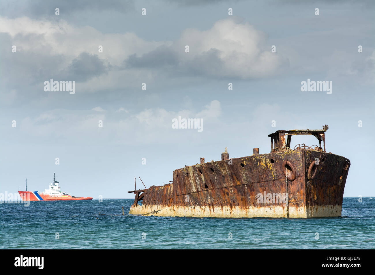 Old wreck with modern ship in the background Stock Photo - Alamy