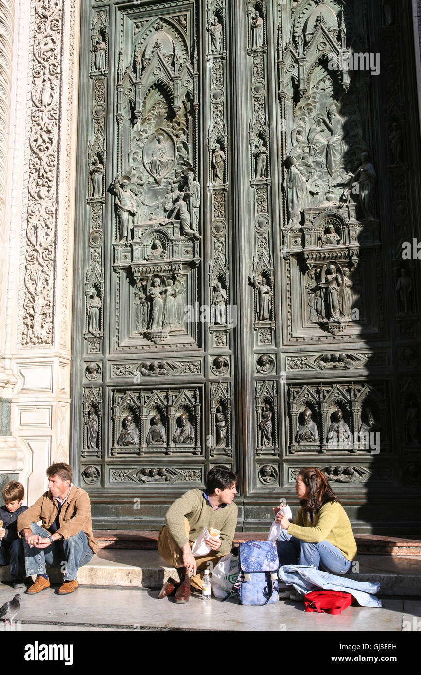 Tourists eating a snack at the main door entrance front of The Duomo ...