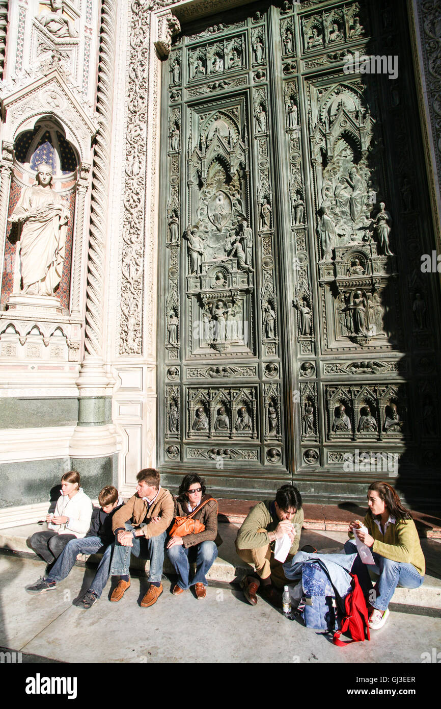 Tourists eating a snack at the main door entrance front of The Duomo ...