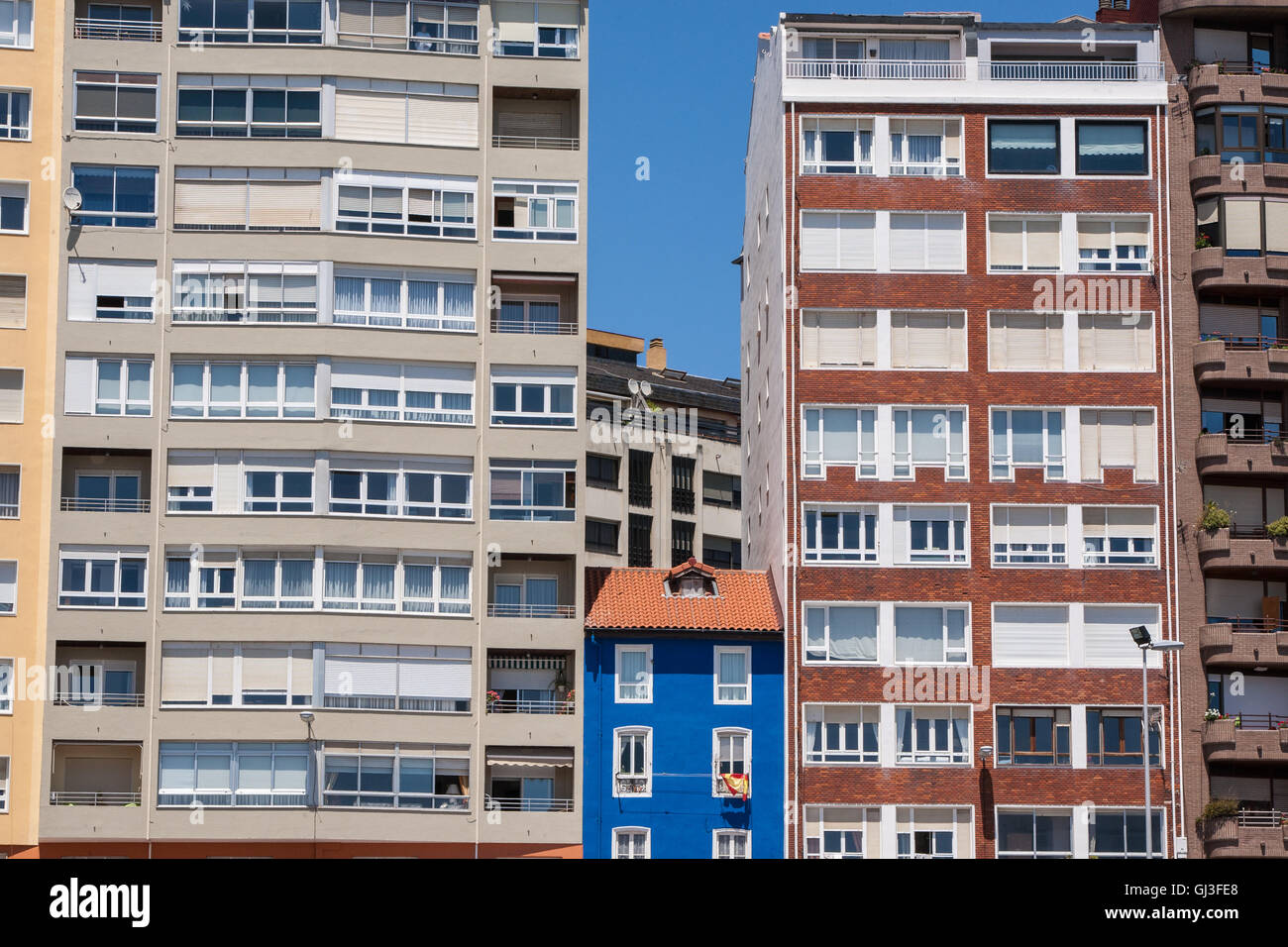 Colourful small short house in between large apartment buildings in ...