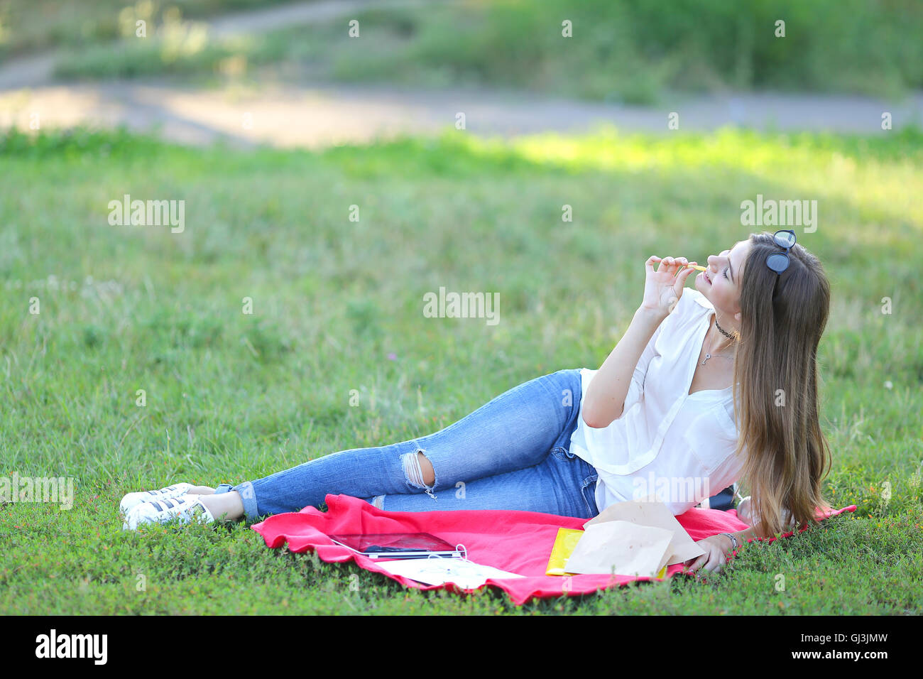 girl lying on the nature and eateth fast food. student working in the ...