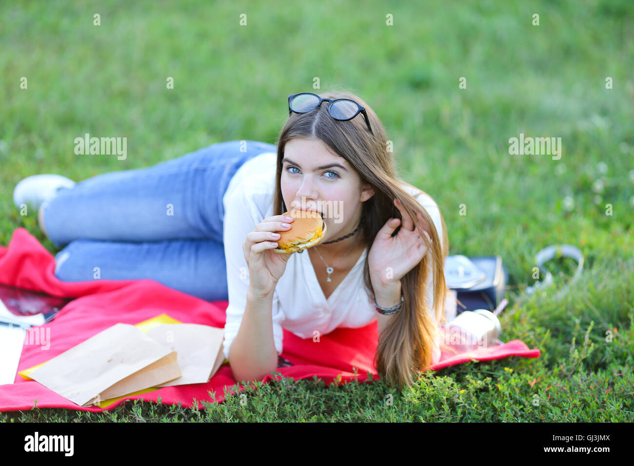 girl lying on the nature and eateth fast food. student working in the ...