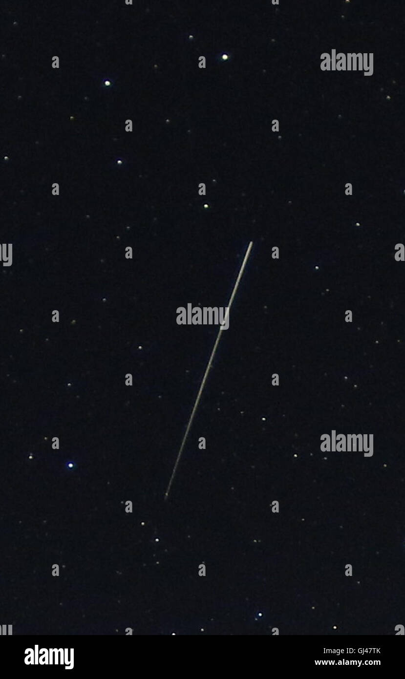 Meteors shoot across the night skies over a wind mill farm during the ...